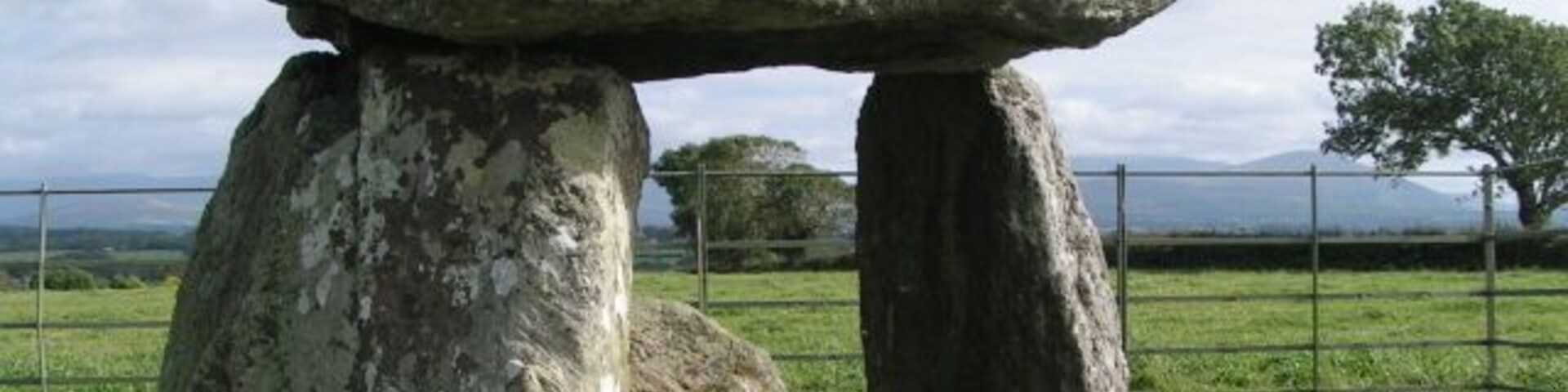 Uma estrutura de pedra vertical em um campo gramado.