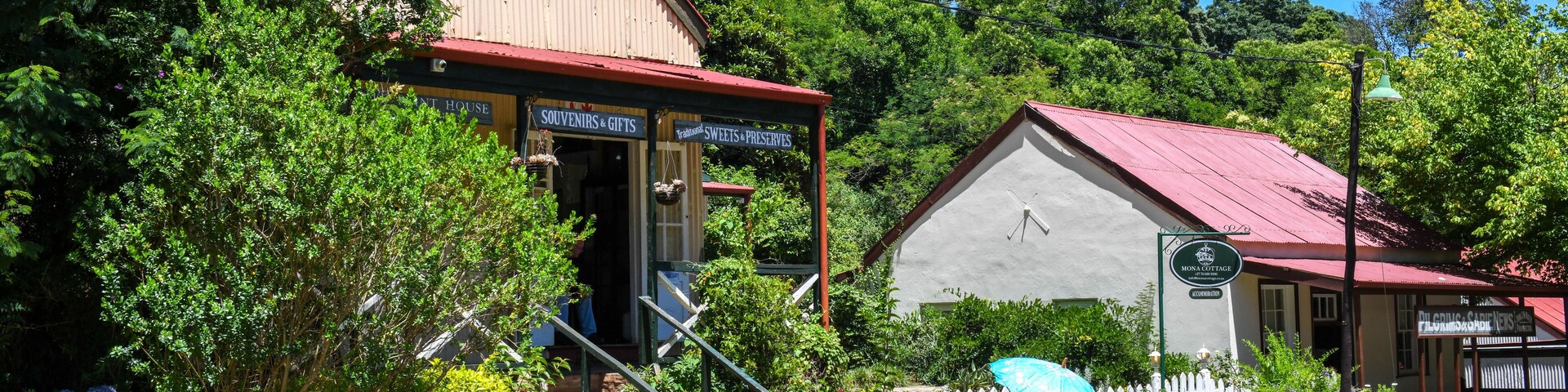 Um edifício rústico com telhado vermelho e placa anunciando lembranças e presentes.