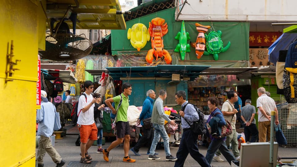 Mercado de rua movimentado com decorações coloridas, incluindo grandes criaturas marinhas infláveis e um toldo verde.