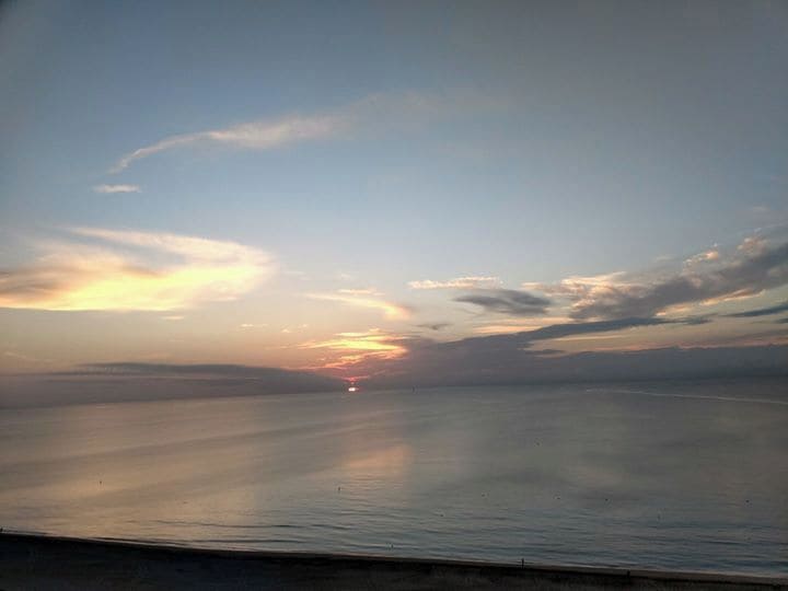 Um pôr do sol sobre um mar calmo, com o horizonte bem definido.