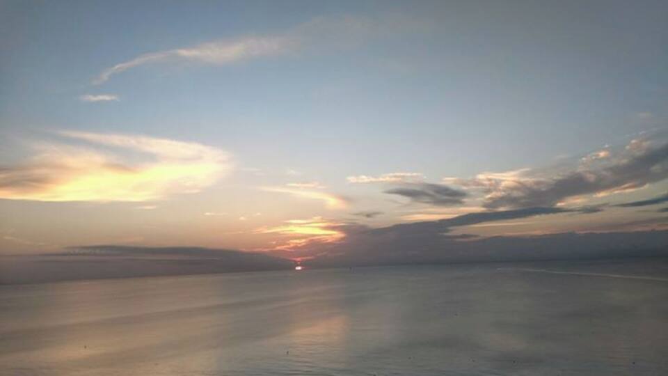Um pôr do sol sobre um mar calmo, com o horizonte bem definido.