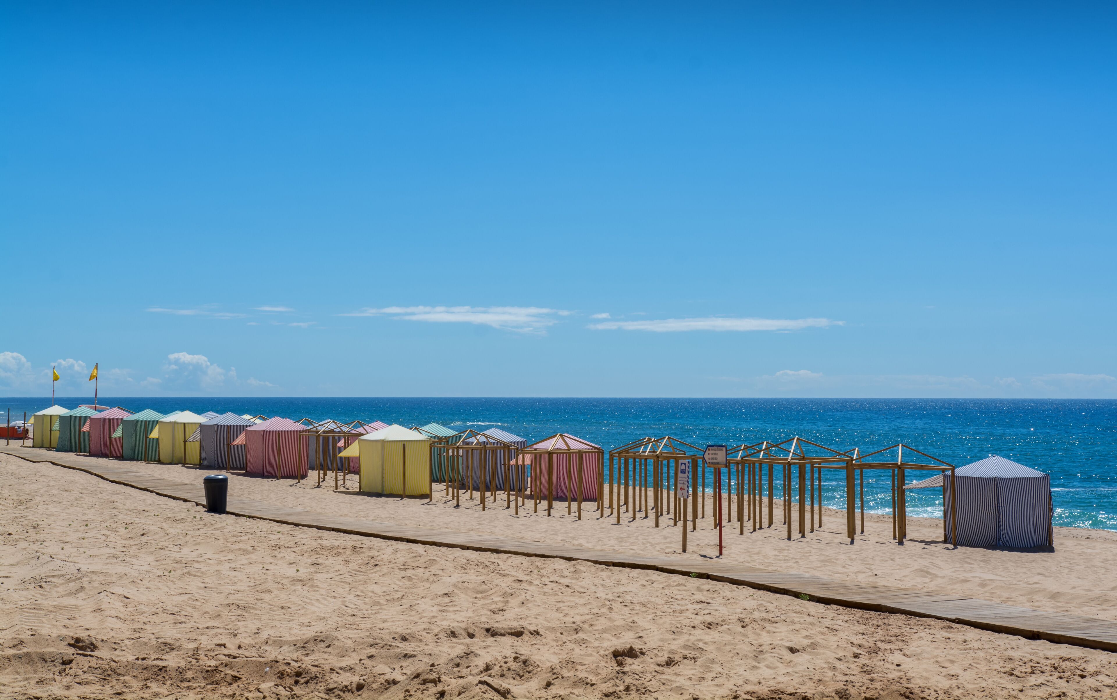 Uma praia com cabanas coloridas e um céu azul límpido.