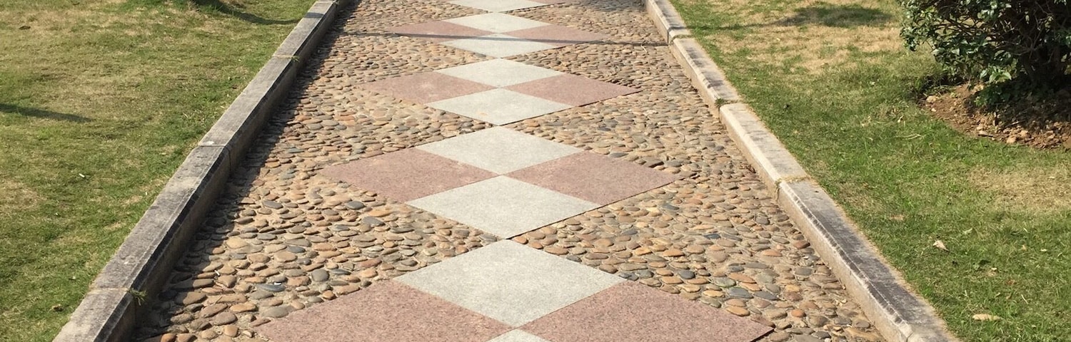 Um caminho ladeado por palmeiras e um piso com desenho.