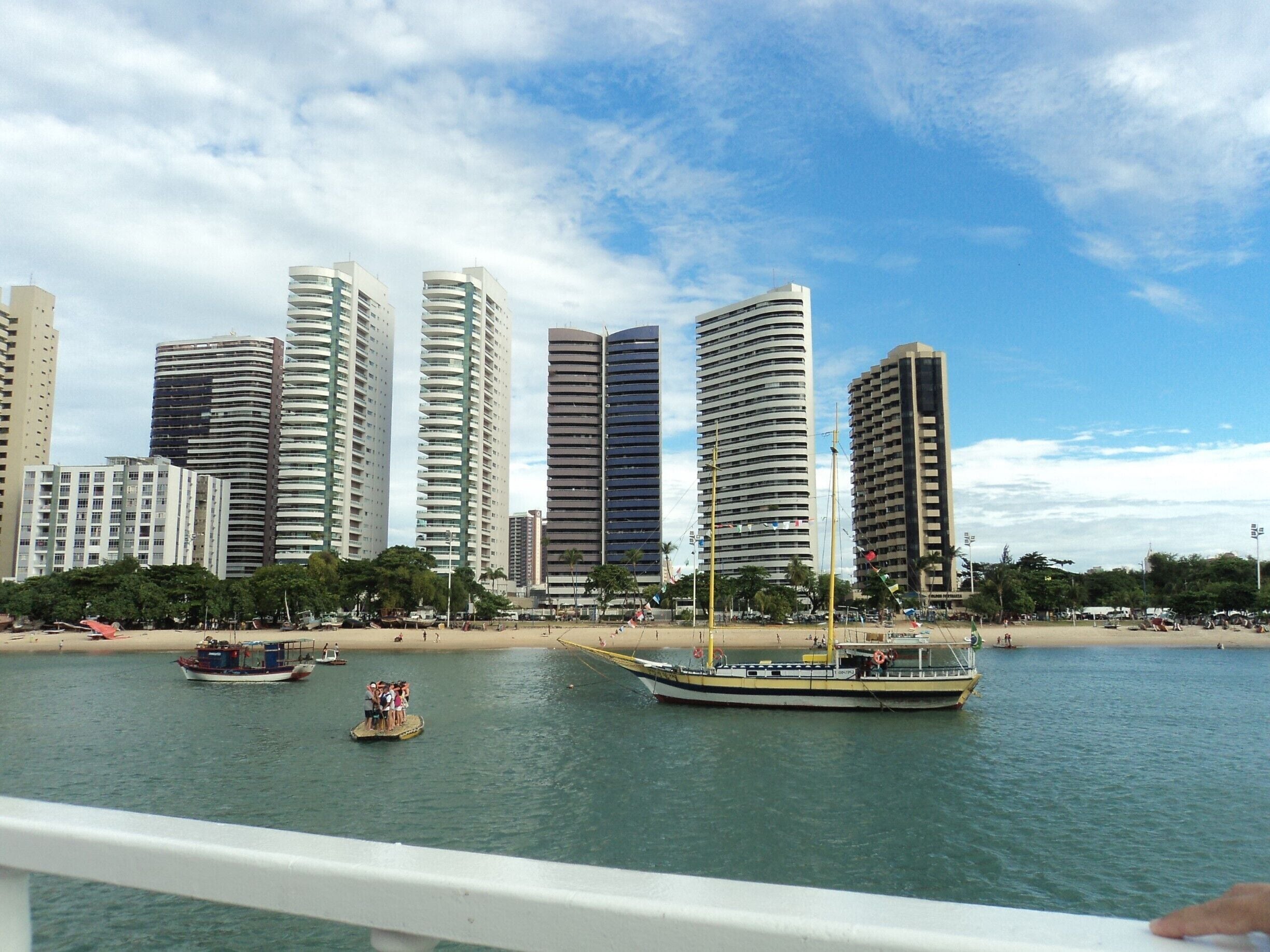 Paisagem costeira com edifícios modernos altos e uma praia.