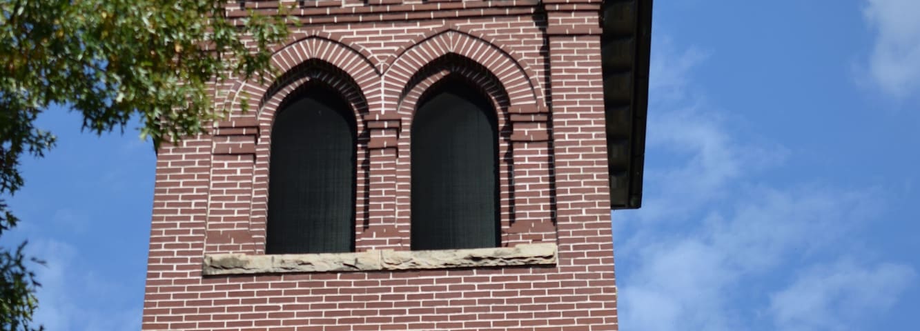 Uma torre de tijolos com telhado pontiagudo e duas janelas em arco.