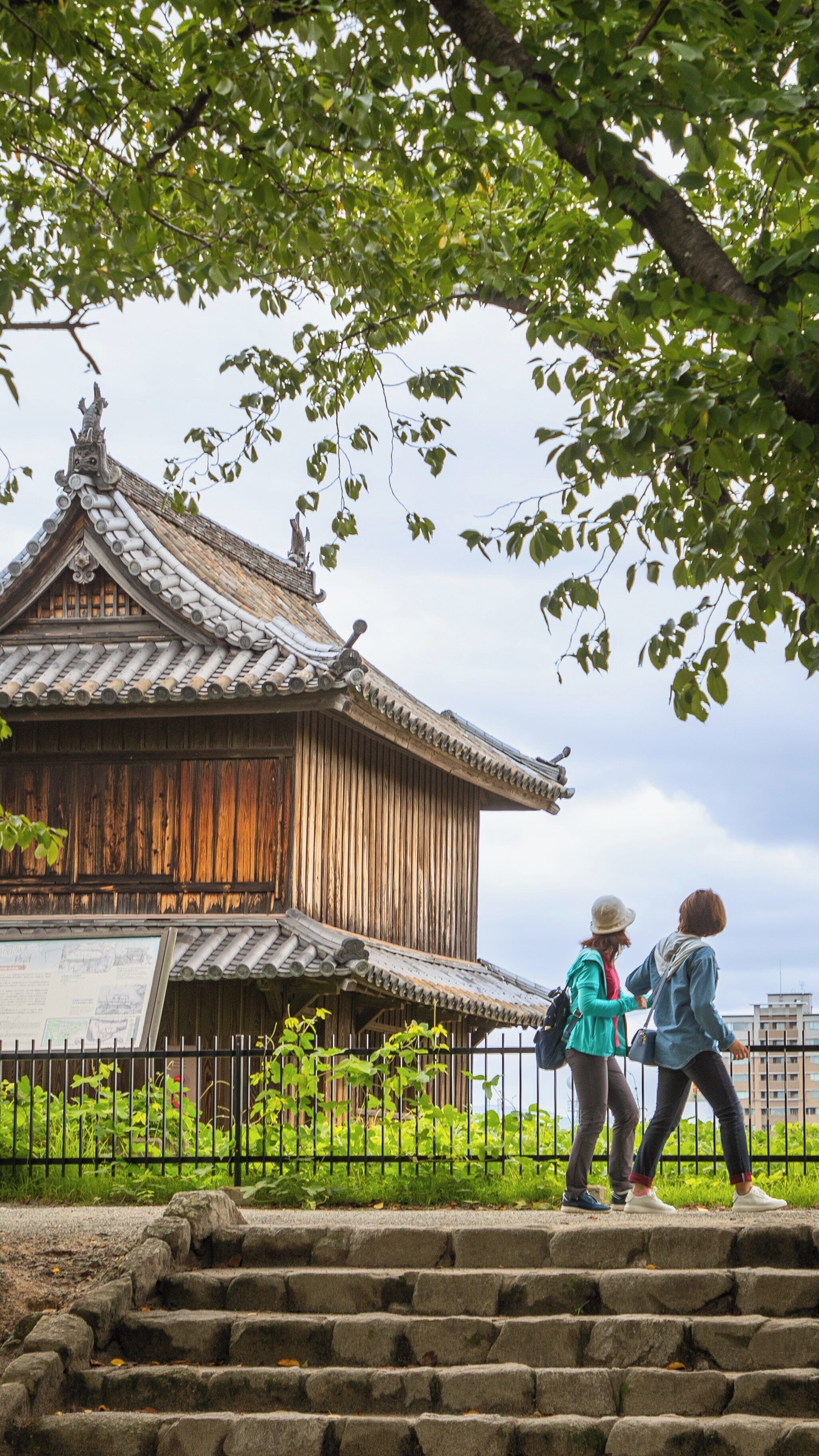 Visitors explore Maizuru Park in Fukuoka, enjoying the beautiful scenery and historic architecture amidst lush greenery on a pleasant day