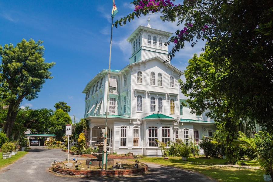 Um edifício branco com telhado verde e um mastro.