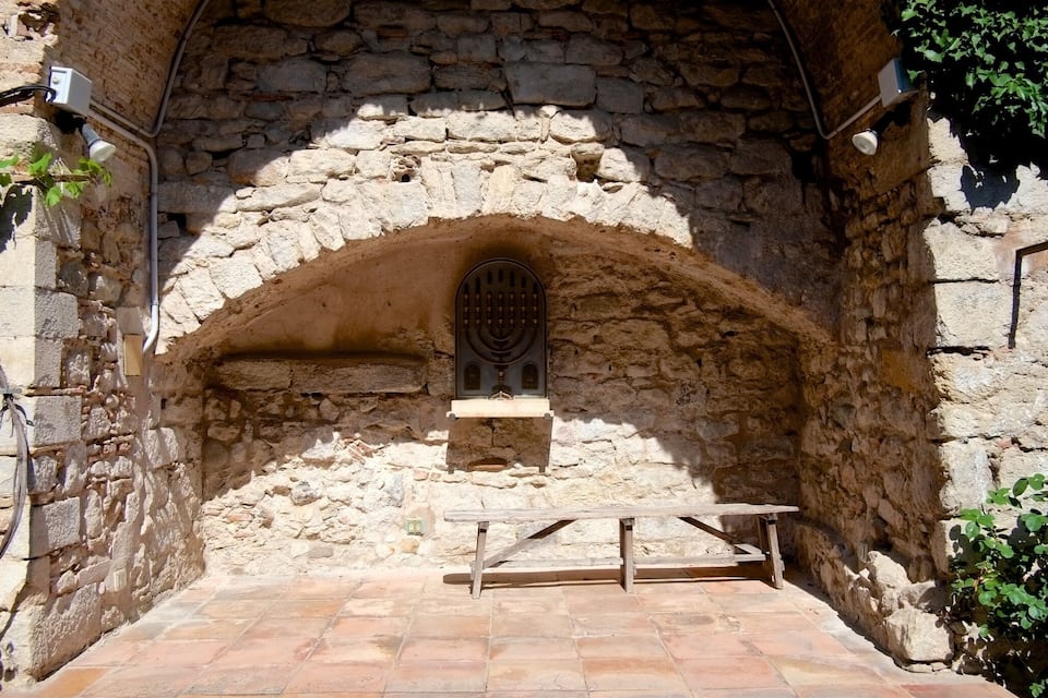 Um arco de pedra com um banco de madeira e uma janela decorativa.