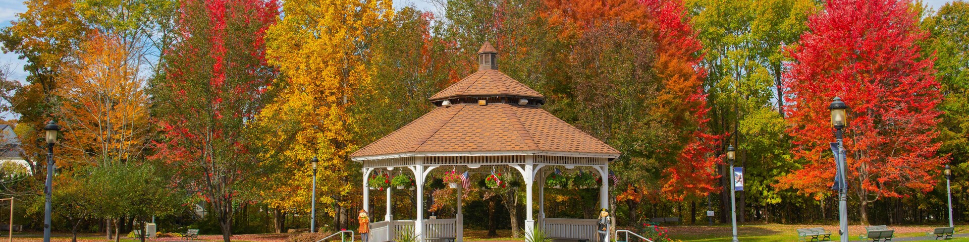 Um gazebo em um parque rodeado por árvores com folhagem outonal.