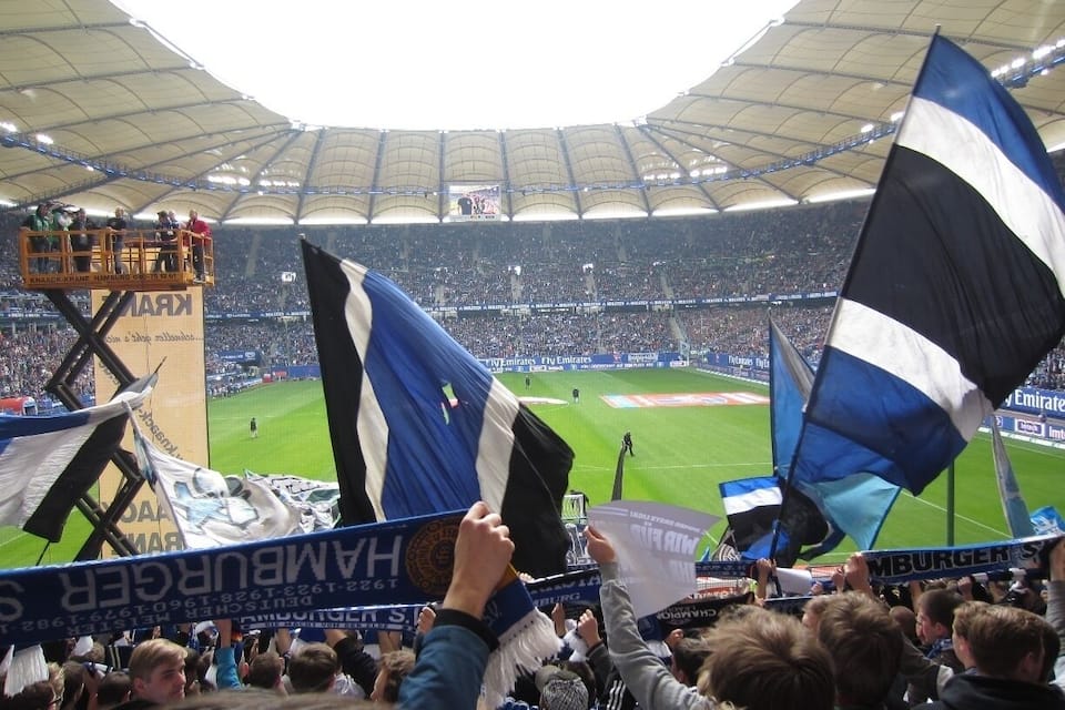 Um estádio lotado de fãs acenando bandeiras e cartazes.