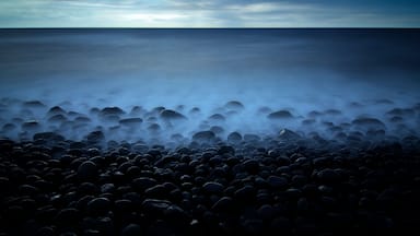Uma costa rochosa com um mar nevoento e um céu nublado.