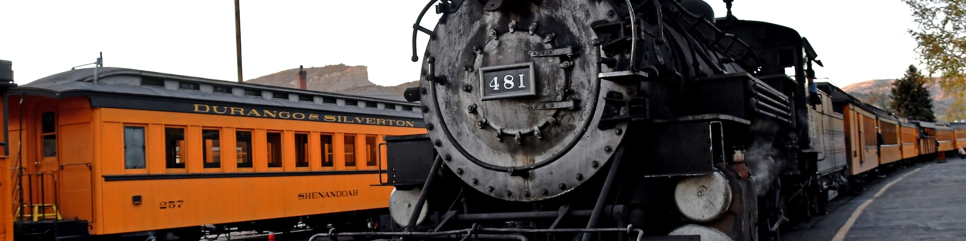 Uma locomotiva a vapor com o número 481 em um trilho de ferro, com um vagão-guarda identificado como "Durango & Silverton".