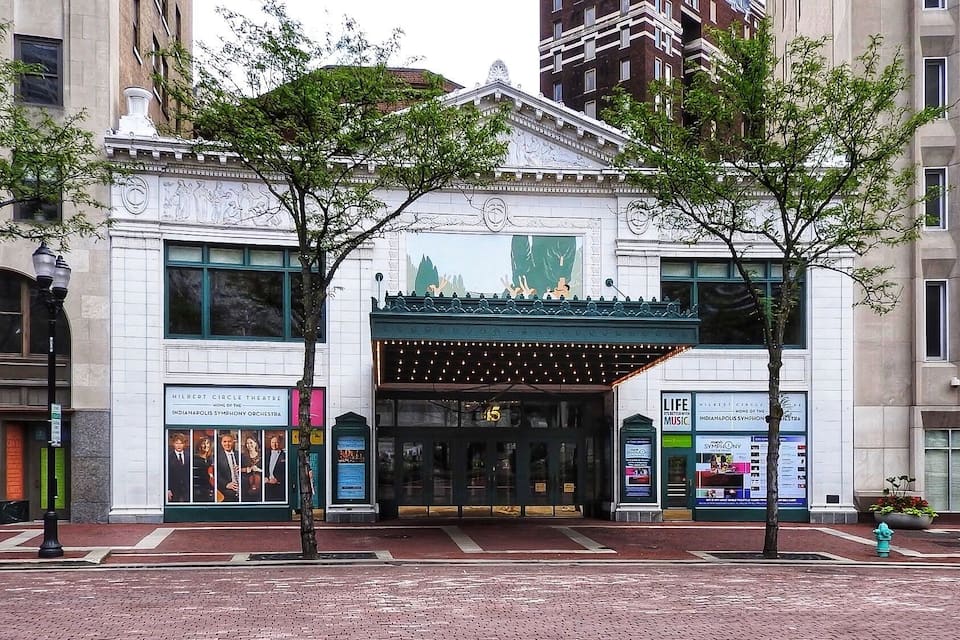 Um teatro com letreiro, árvores e calçada de tijolos.