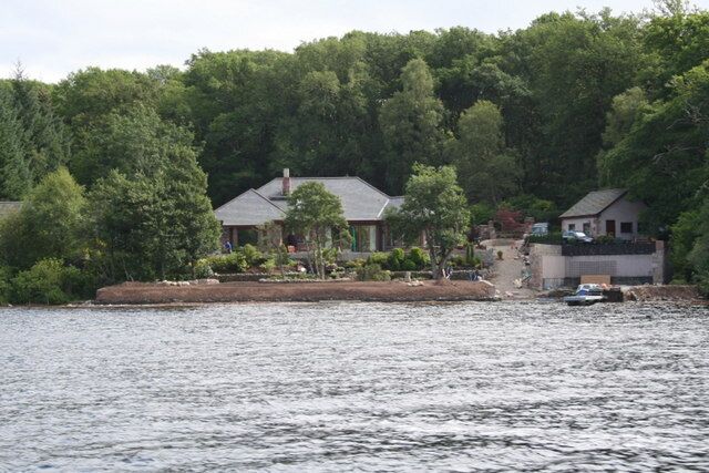 Uma casa à beira do lago, rodeada por uma floresta densa.