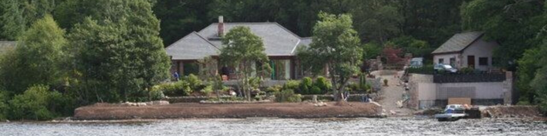 Uma casa à beira do lago, rodeada por uma floresta densa.