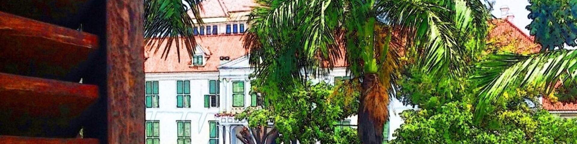 Uma praça com palmeiras, um edifício branco com persianas verdes e pessoas caminhando.