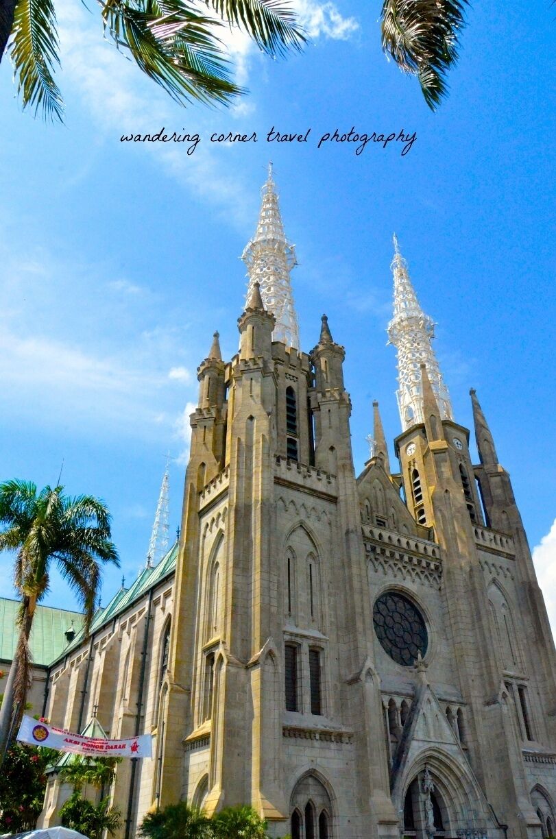 Uma catedral grande com três torres e um telhado verde.