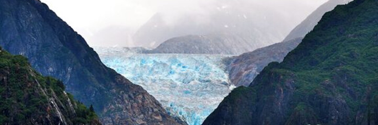 Um glaciar com icebergs em um fiorde, rodeado por montanhas.