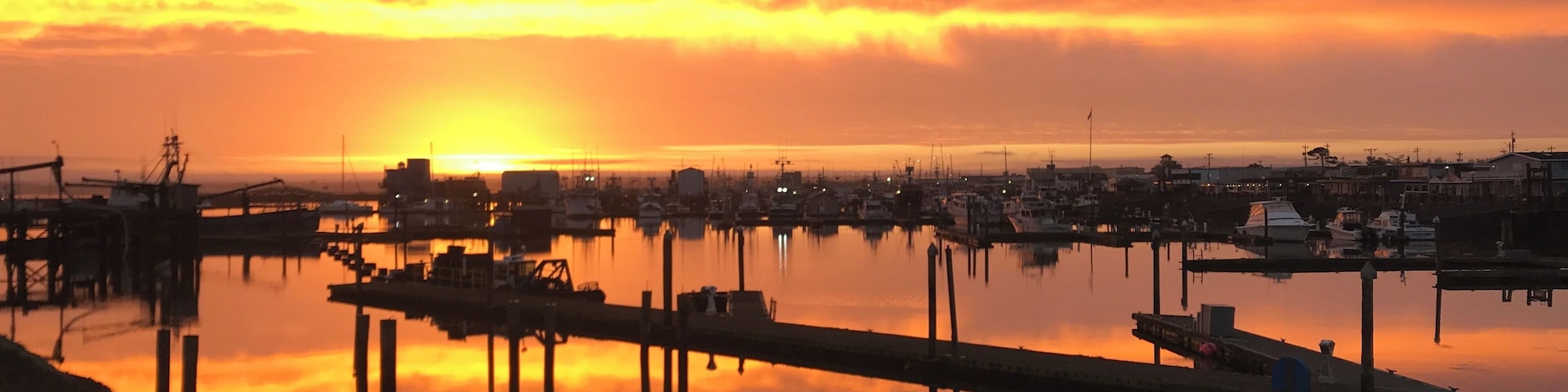 Um pôr do sol sobre um cais com barcos e docas.