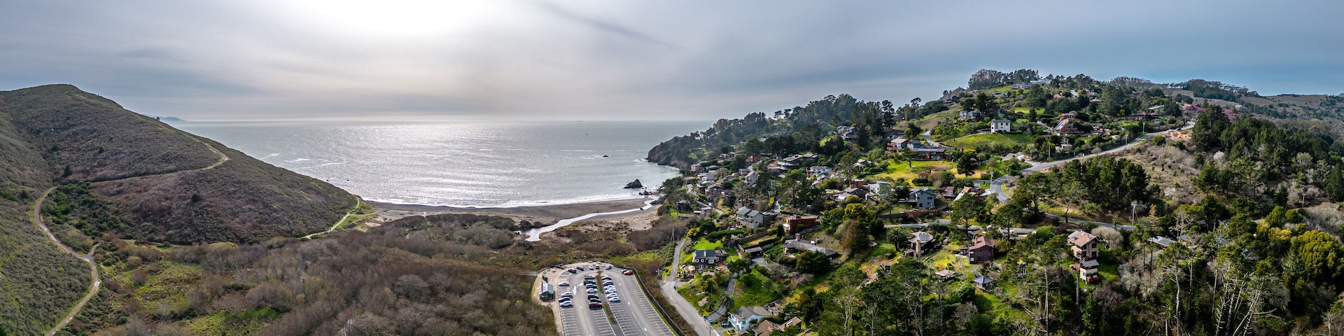Uma estrada costeira com casas numa encosta, com vista para o oceano.