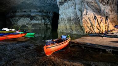 Caiaques dentro de uma gruta com um píer de madeira.