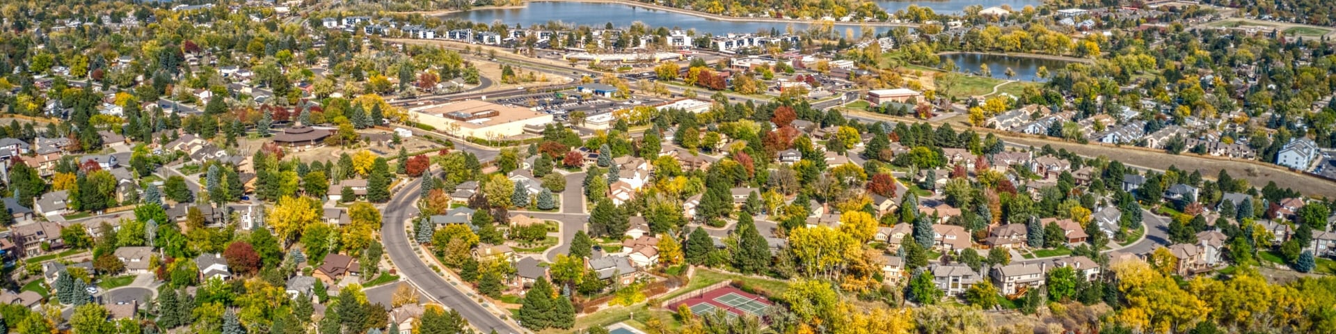 Vista aérea de uma área suburbana com casas residenciais, estradas e uma grande massa de água.
