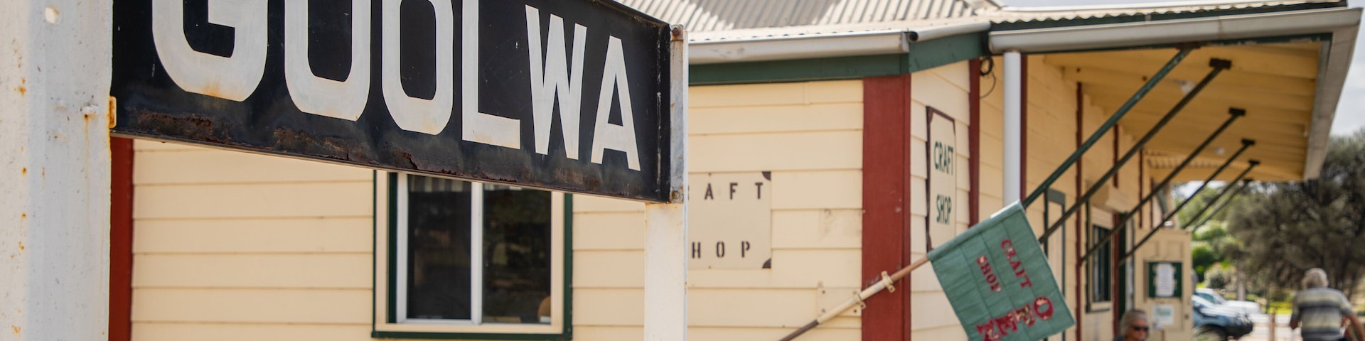 Uma placa com a inscrição 'Goolwa' e uma placa de loja de artesanato.