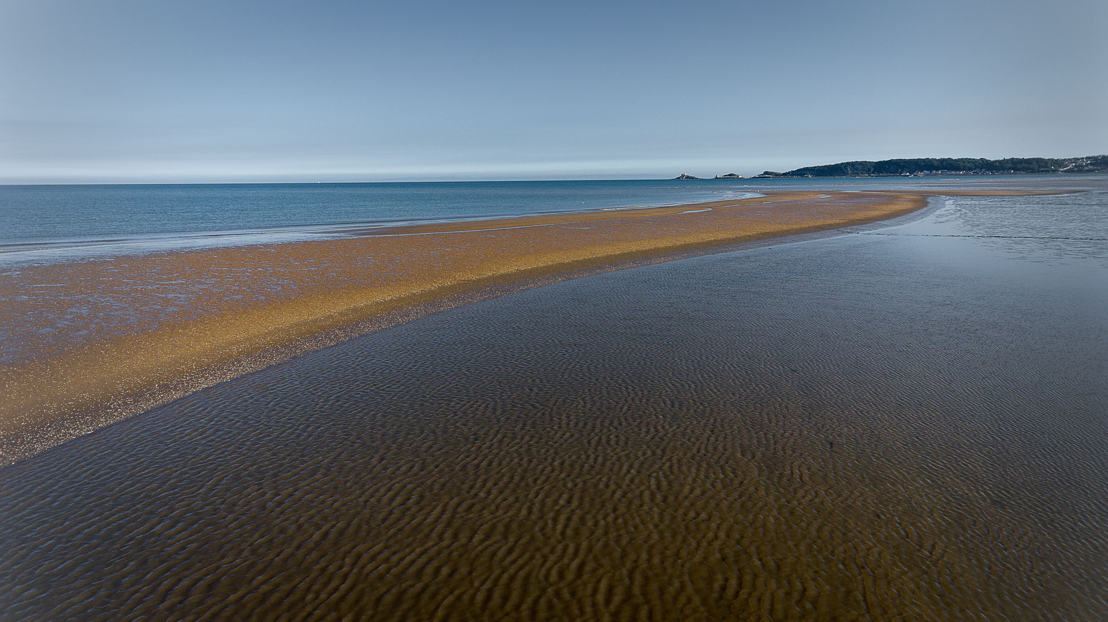 Uma praia com areia molhada e mar calmo.