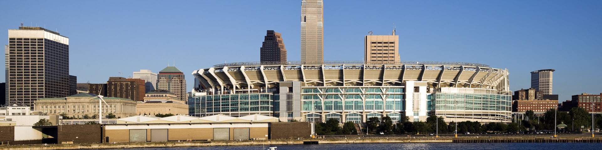 Paisagem urbana à beira-mar com um estádio em destaque e diversos edifícios modernos.