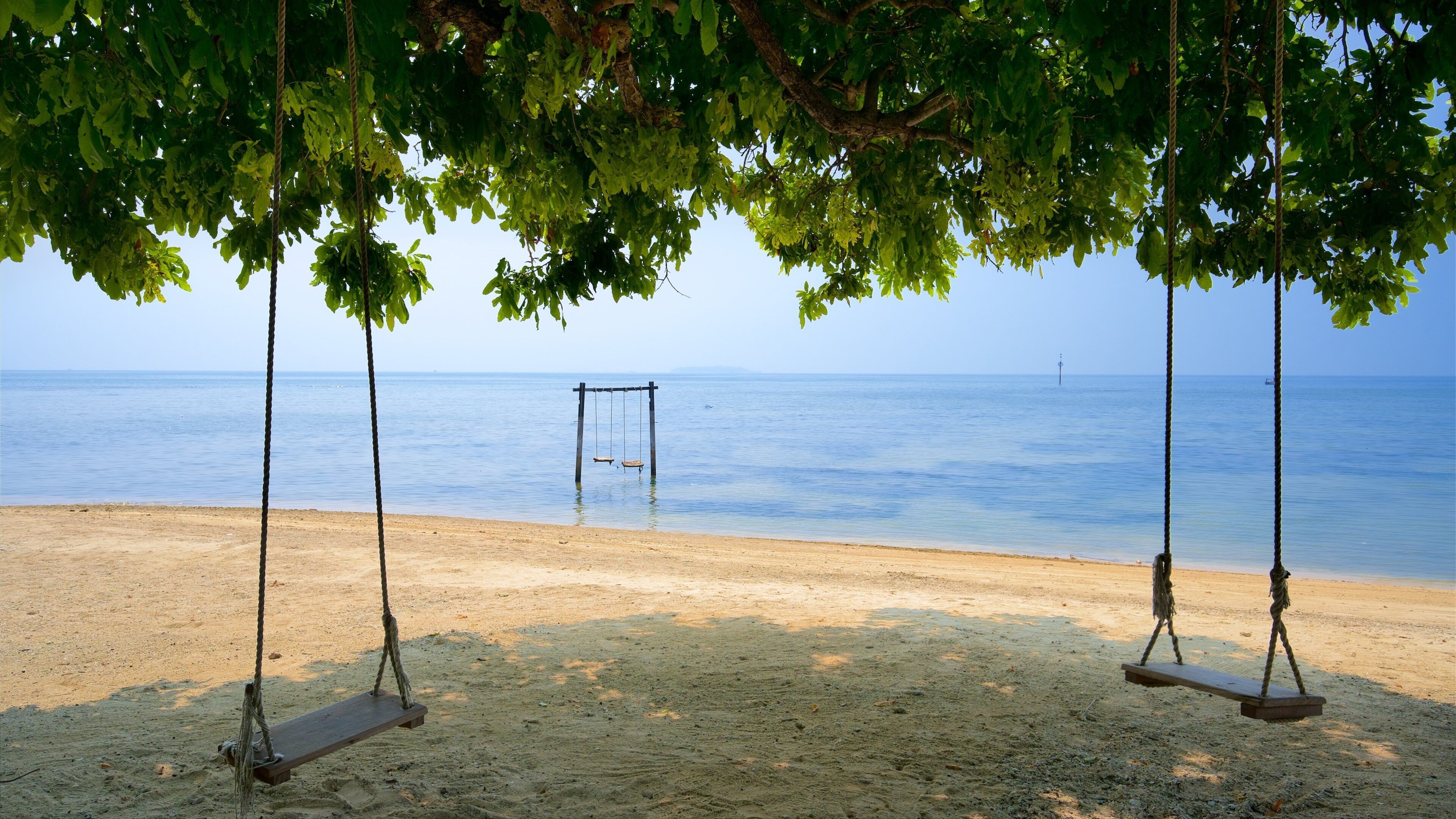 Uma praia com baloiços e parque infantil.