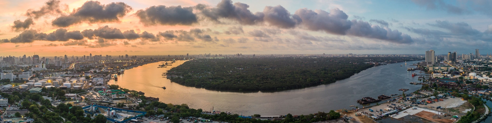 Um rio serpenteando por uma cidade com zonas industriais e intenso desenvolvimento urbano.