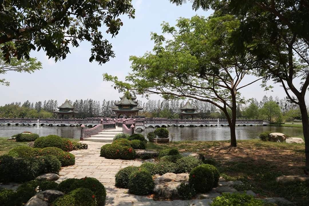 Um jardim chinês tradicional com uma ponte, pagodes e um lago.