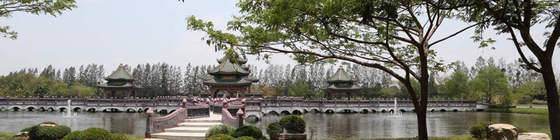 Um jardim chinês tradicional com uma ponte, pagodes e um lago.