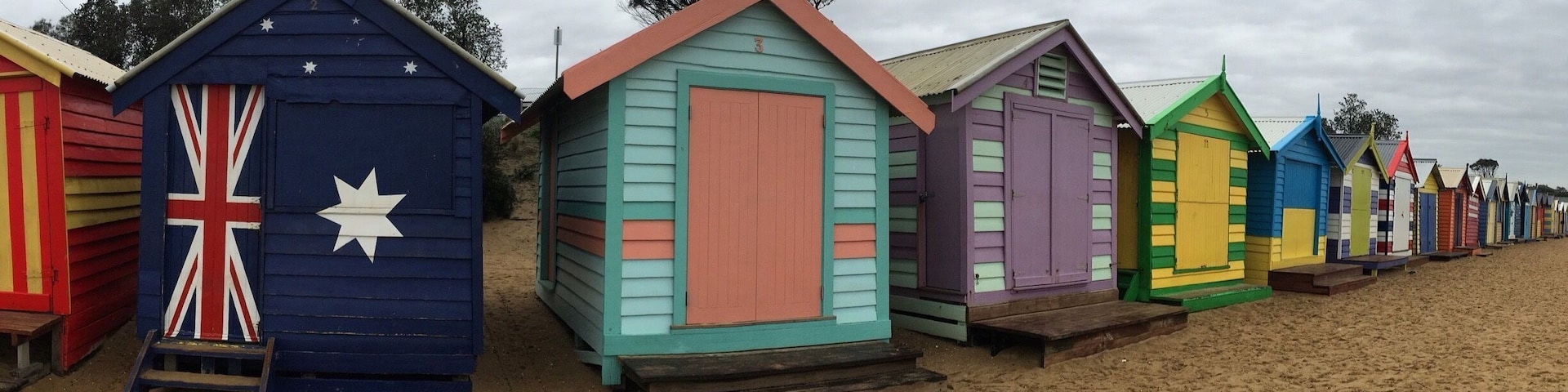 Panoramic view of the brightly-coloured Brighton Beach shacks.
Try to pick a favourite... My fave has a big crab painted on the doors! 🦀