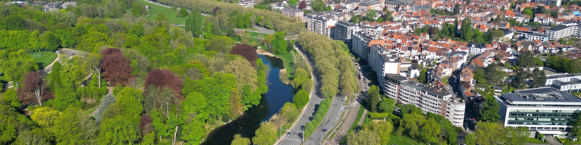 Vista aérea de uma cidade com rio, parques verdes e uma mistura de arquitetura moderna e tradicional.