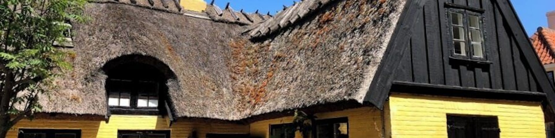 Um edifício tradicional com telhado de palha e paredes amarelas.