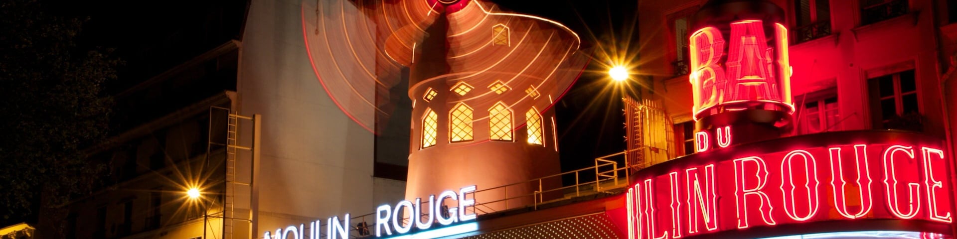 Colorful night view of Moulin Rouge in Montmartre, Paris showcasing lively atmosphere and iconic cabaret culture