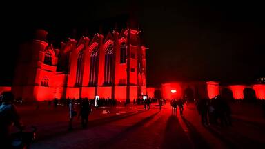 Um edifício grande e iluminado com arquitetura gótica à noite.