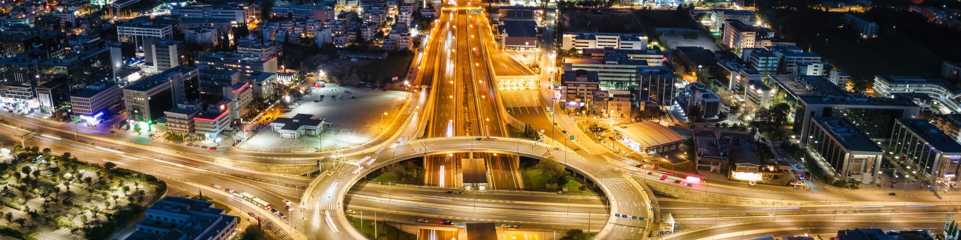 Paisagem urbana noturna com uma rotatória em destaque e várias autoestradas.