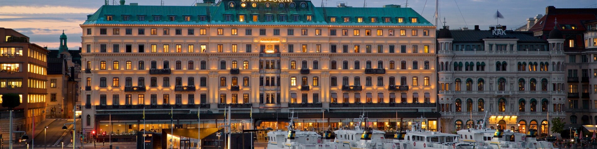 Uma orla marítima com um hotel grande e várias embarcações atracadas.