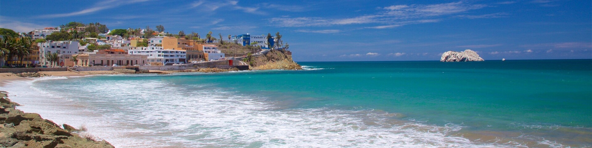 Uma cidade costeira com edifícios construídos em um penhasco com vista para águas azul-turquesa.
