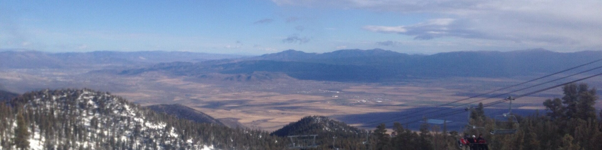 Paisagem nevada de montanhas com um teleférico e céu limpo.