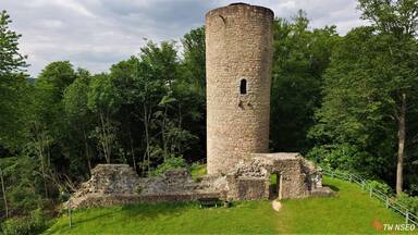 Uma torre de pedra rodeada por vegetação exuberante.
