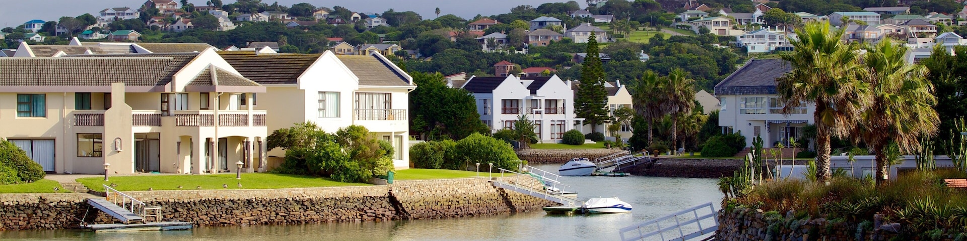 Uma área residencial à beira-mar, com casas, uma ponte e barcos.