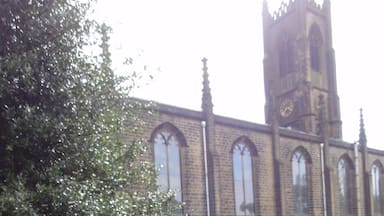 Uma igreja com uma torre alta e janelas em arco, cercada por um cemitério com lápides.