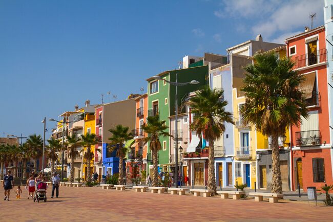 Uma rua colorida ladeada por palmeiras e edifícios.