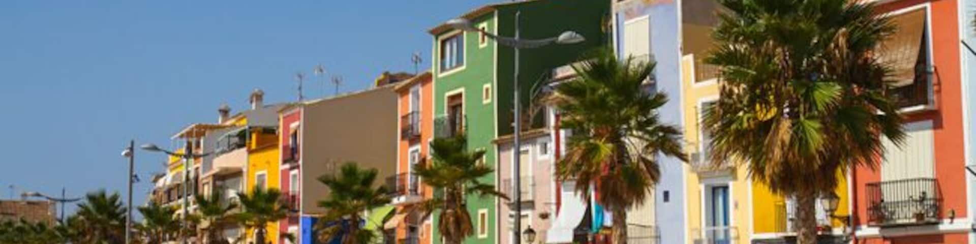 Uma rua colorida ladeada por palmeiras e edifícios.