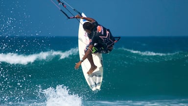 Uma pessoa praticando kitesurf em uma onda.