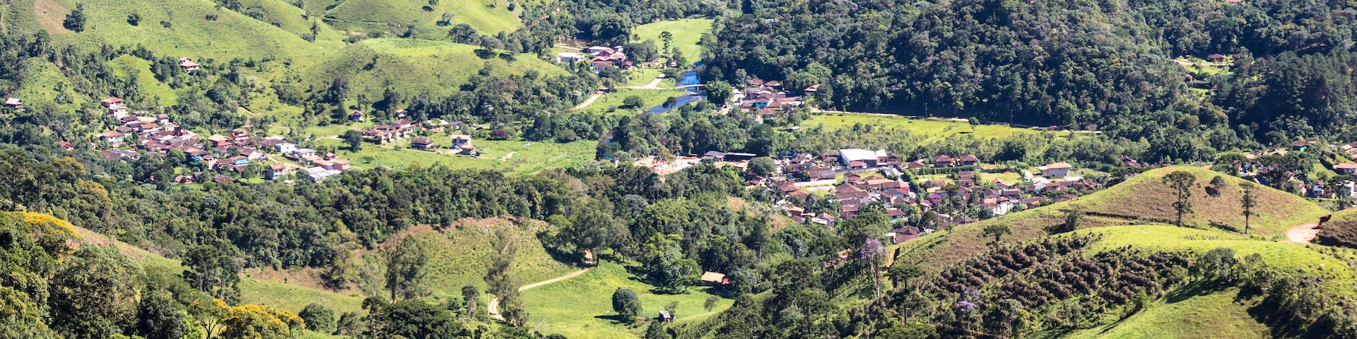 Um vale verdejante com casas dispersas e um rio.