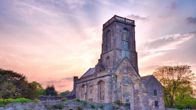 Uma igreja de pedra histórica com uma torre de sino alta e janelas em arco.